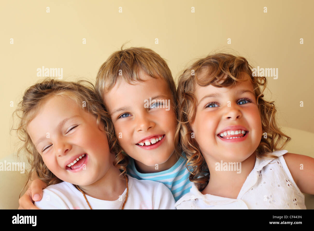 Smiling children three together in cosy, girl at left closed eyes Stock ...