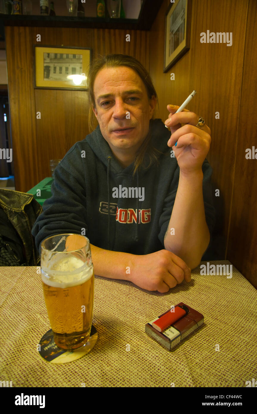 Man in his 30s drinking beer and smoking cigarette in traditional Czech ...