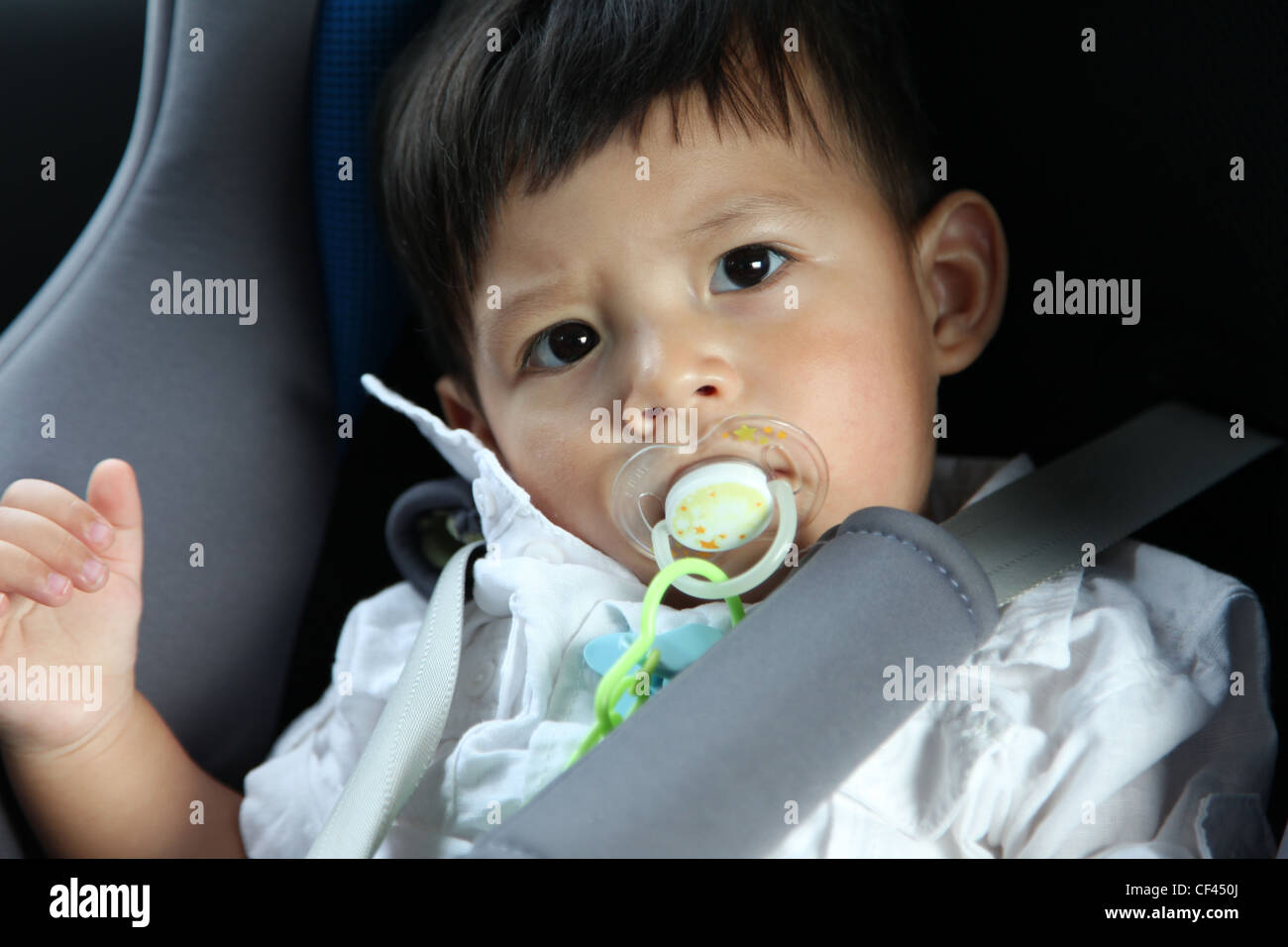 Cute Baby Eurasian Boy in a Baby seat car has his pacifier in his mouth ...