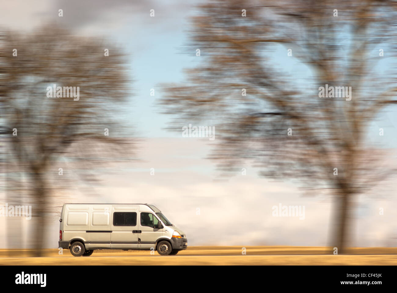 car on road between yellow and green trees with cloudy sky Stock Photo ...