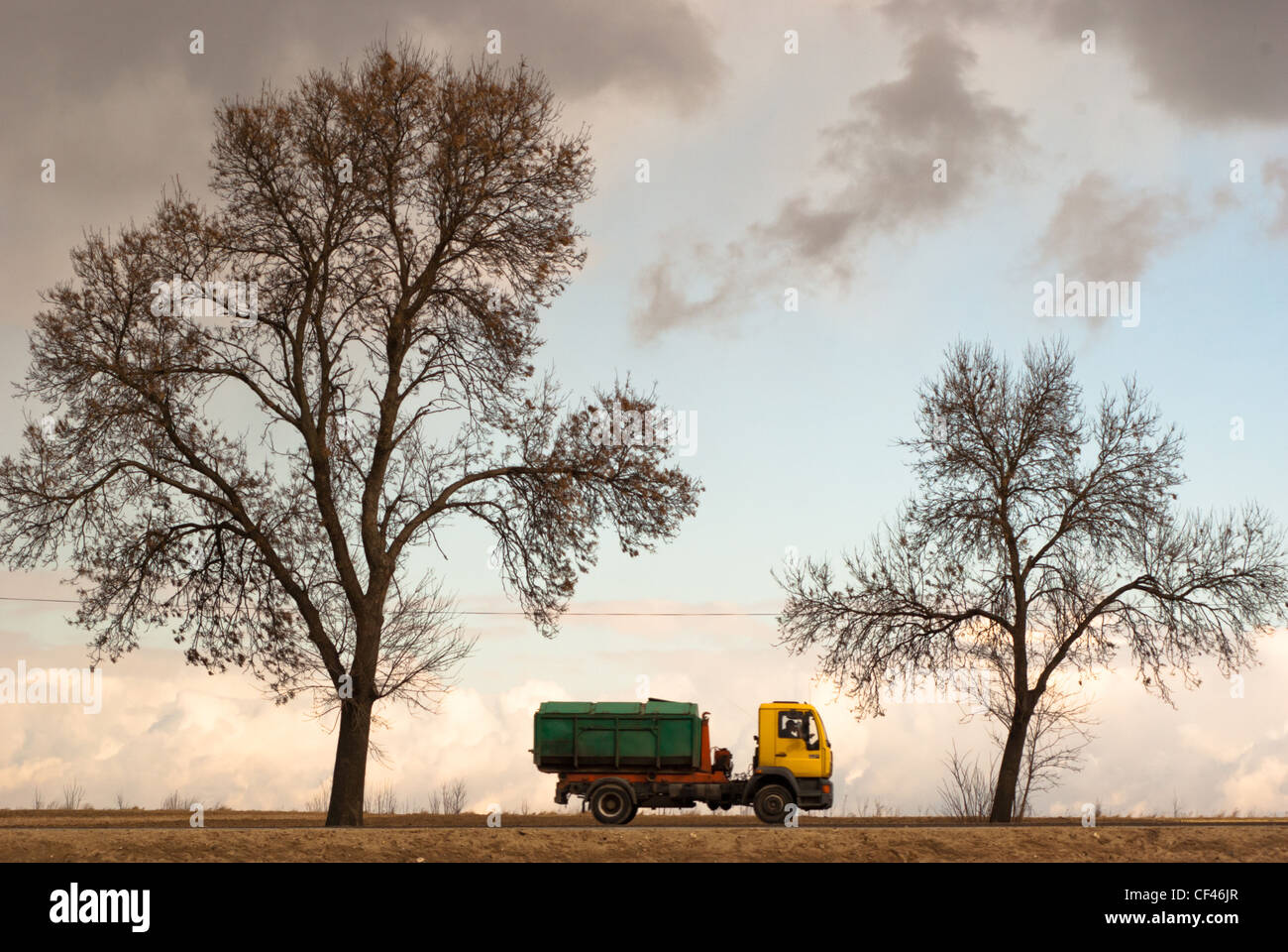 car on road between yellow and green trees with cloudy sky Stock Photo ...