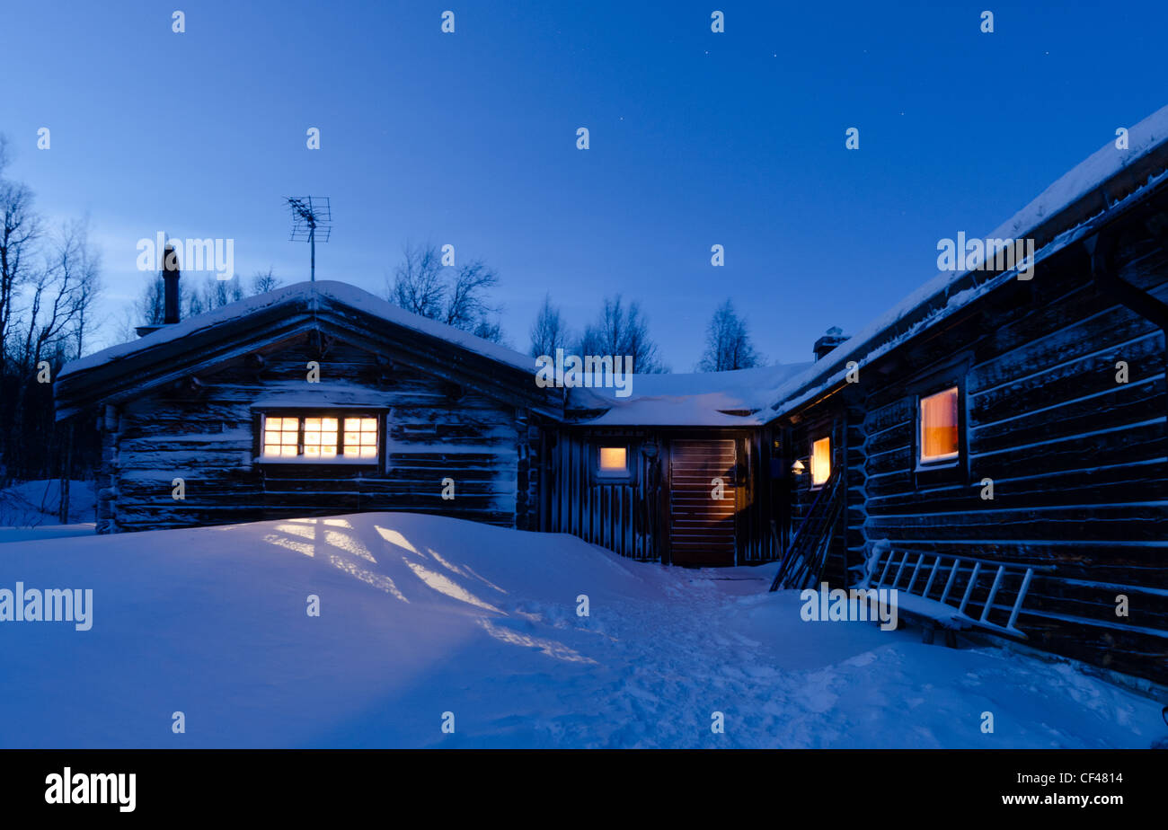 Winter log-cabin with lots of snow and warm light indoors Stock Photo ...