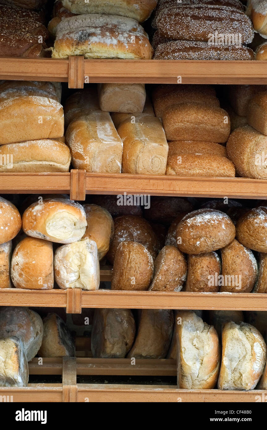 Shelves with loaves of fresh baked bread on display in bakery shop ...