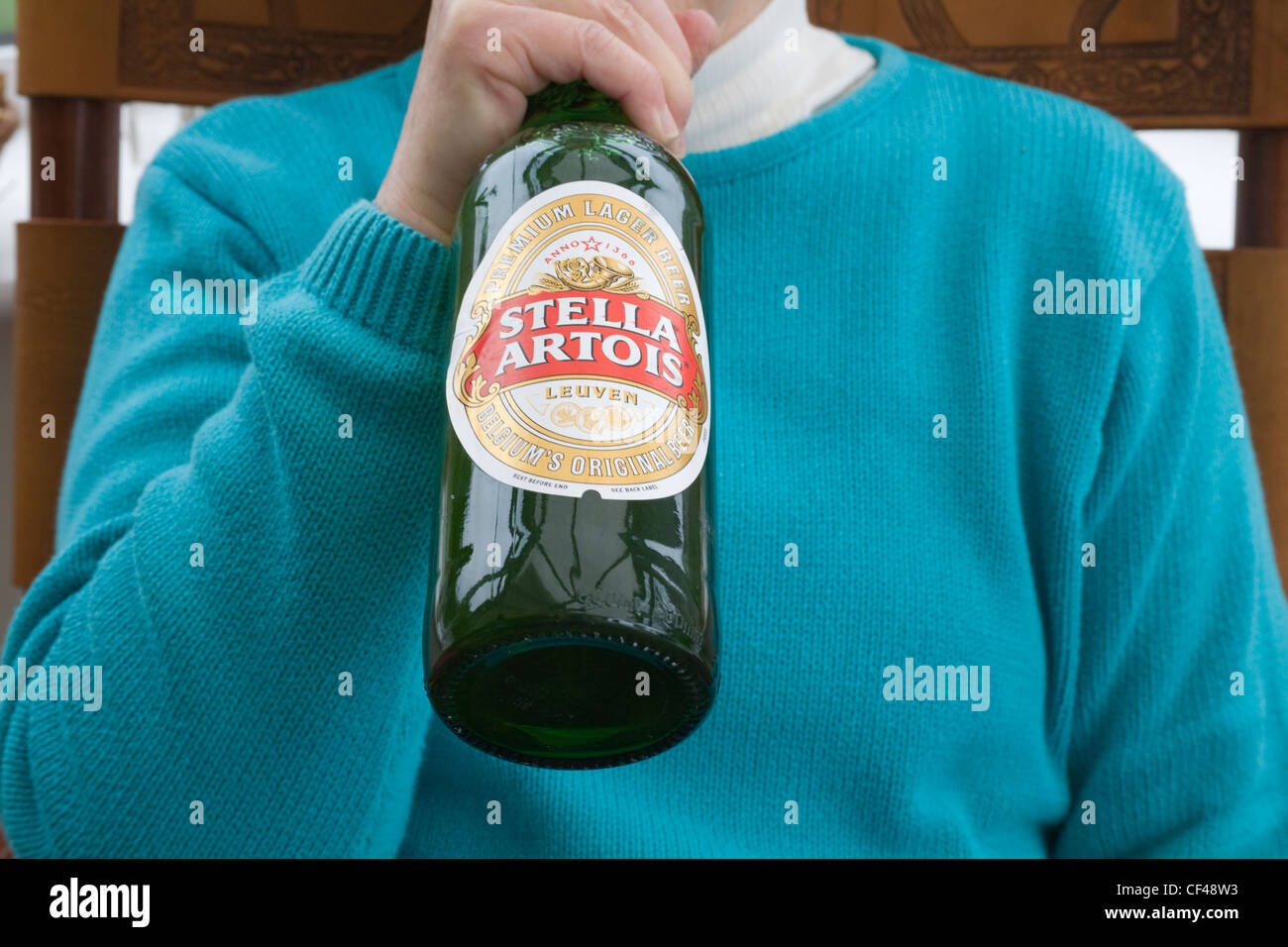 Close up woman sitting chair drinking from Stella Artois bottle lager ...