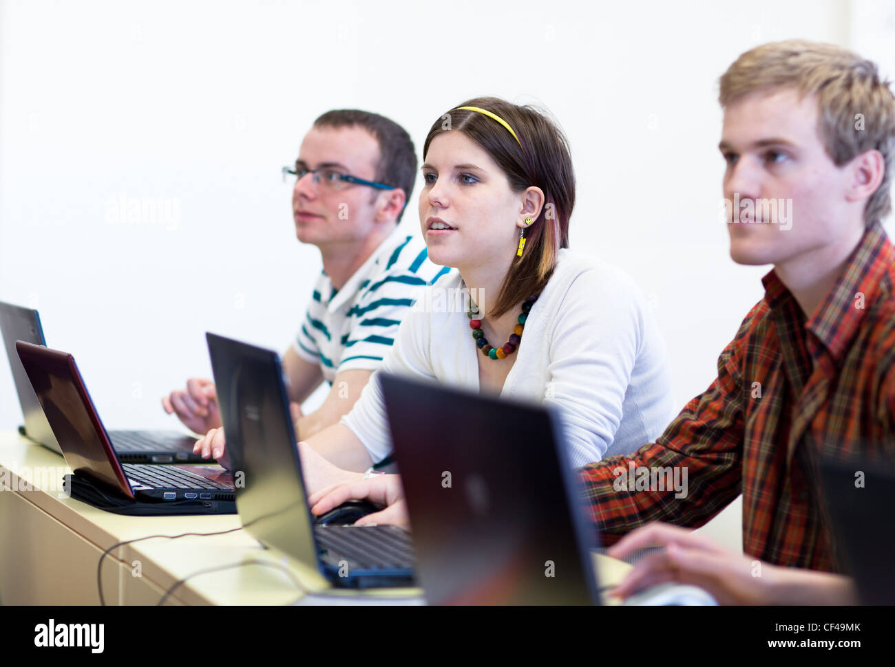 young, pretty female college student sitting in a classroom full of ...