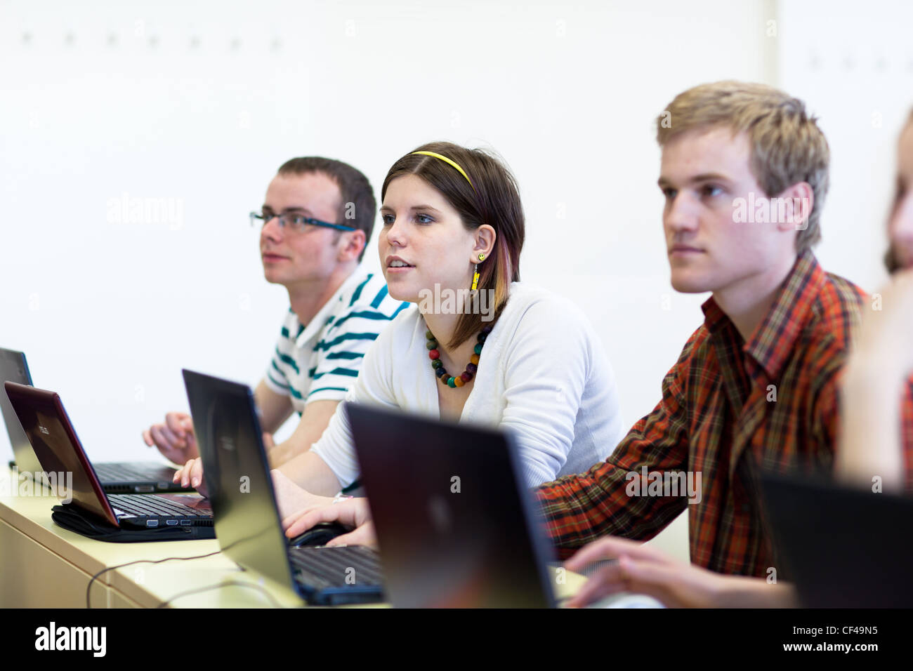 young, pretty female college student sitting in a classroom full of ...