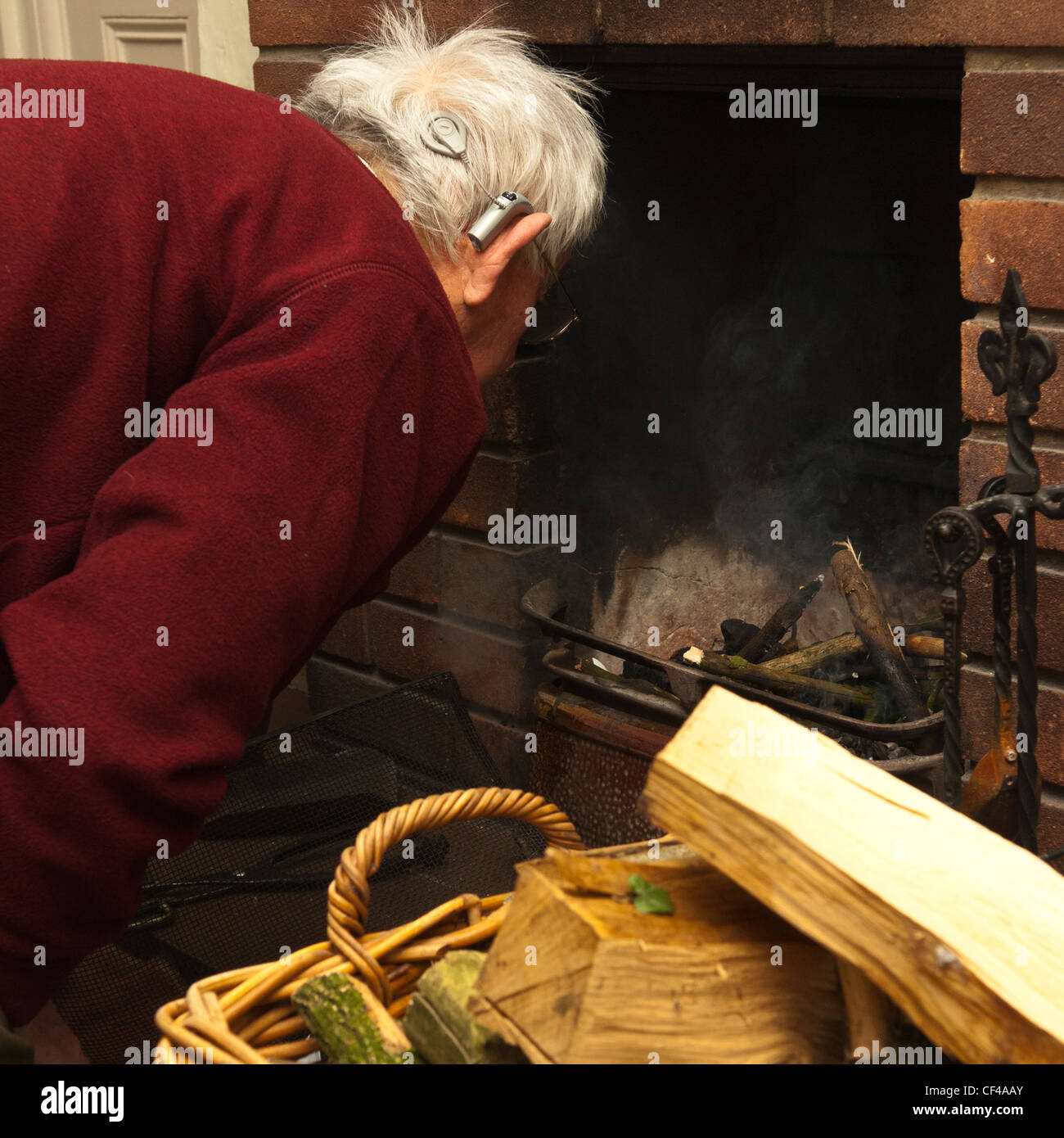 A senior elderly man in his 80's stoking an open fire at home in ...