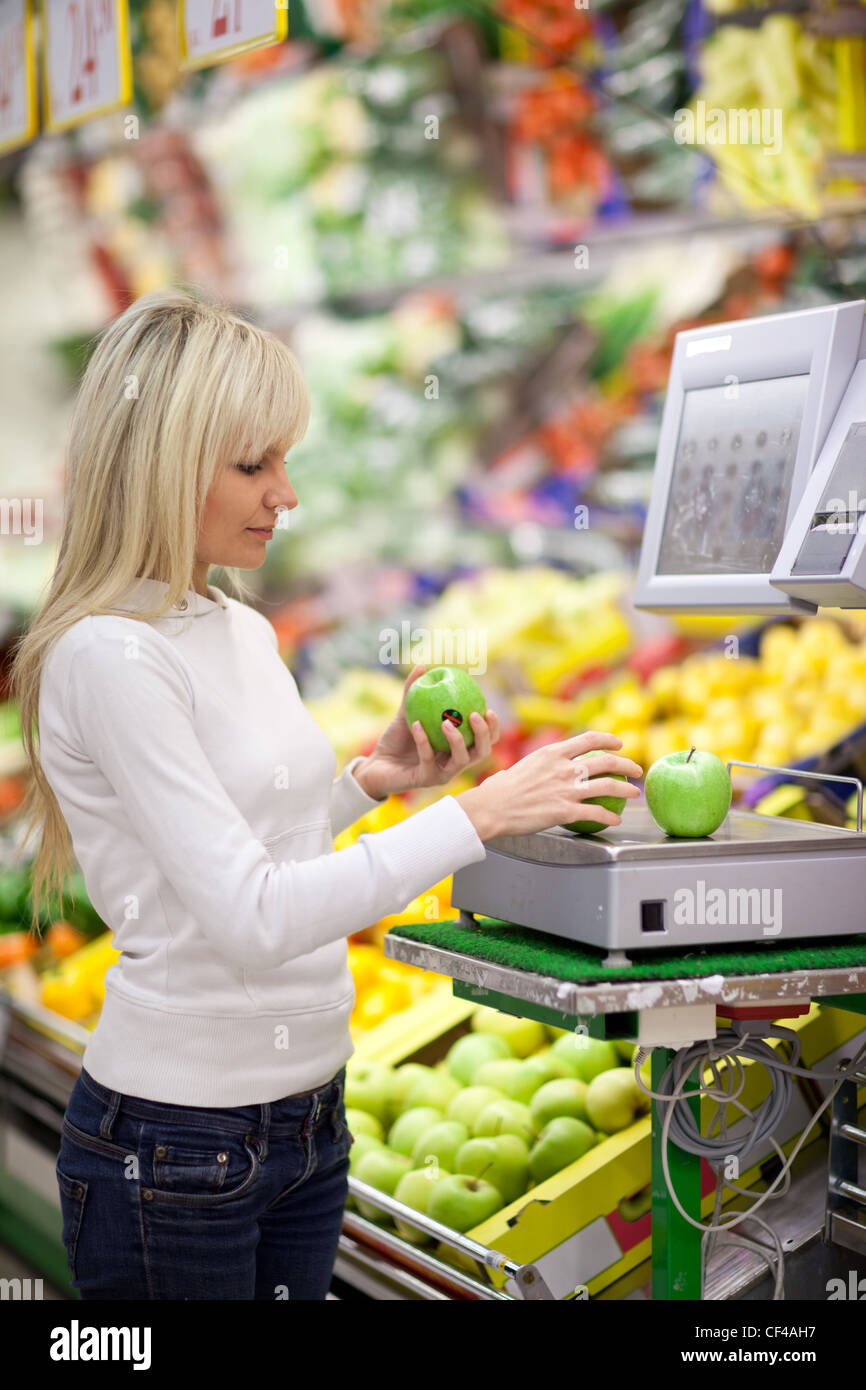 Beautiful young woman shopping for fruits and vegetables in produce ...