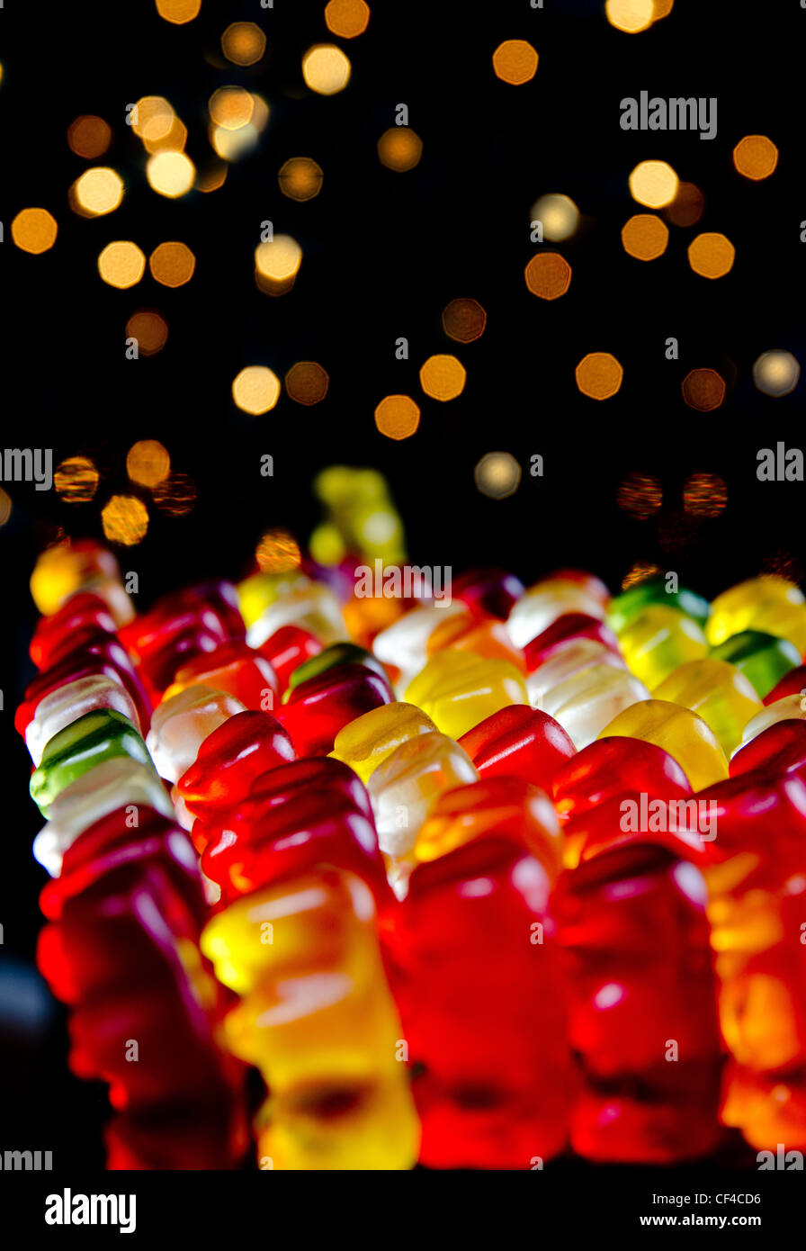 Army of sweet colorful jelly teddies with blinking lights on black ...