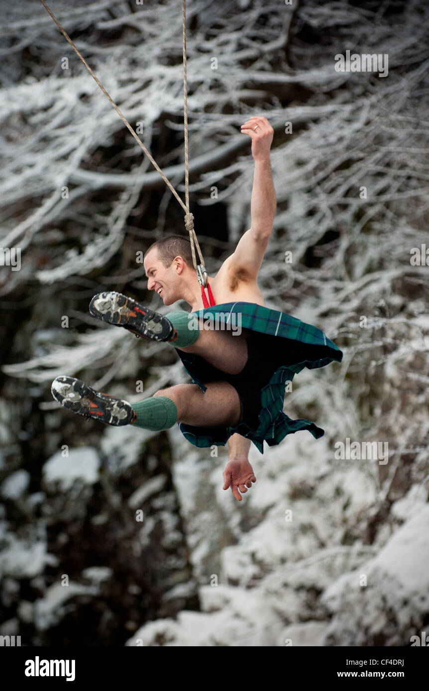 Man in a kilt swings from bridge holding a flare Stock Photo - Alamy