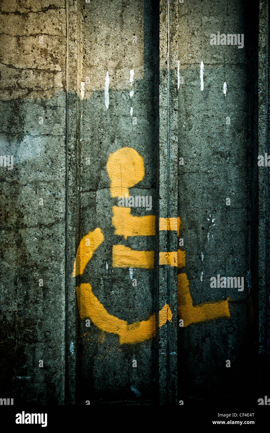 Symbol of person in wheelchair spray-painted onto a dark, old, decrepit ...