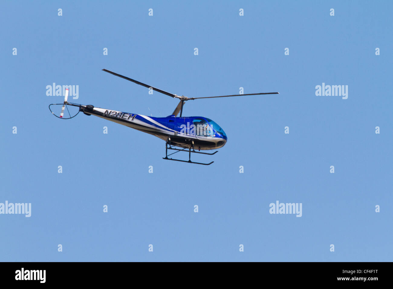Blue small helicopter flying on a blue sky Stock Photo - Alamy