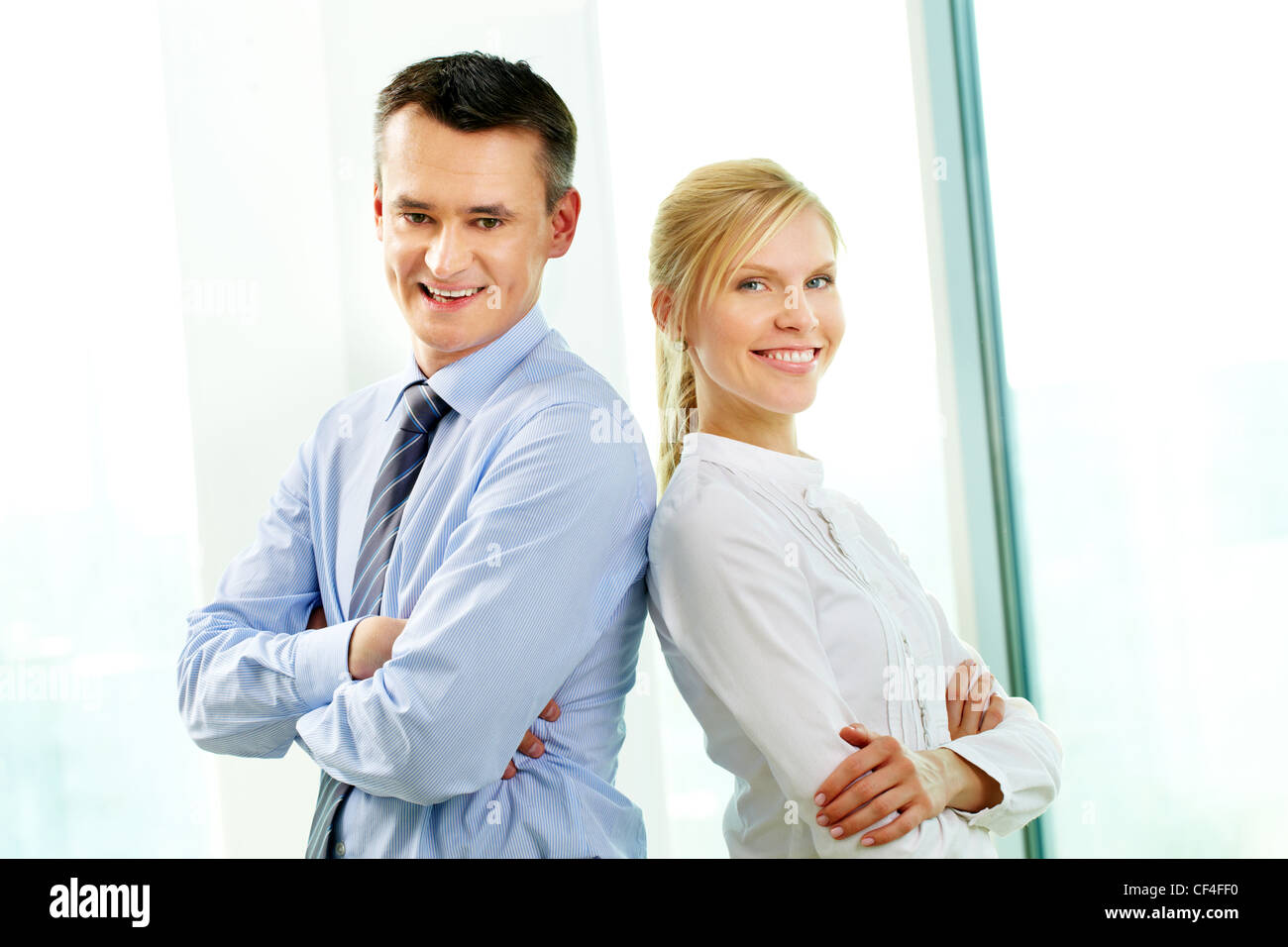 Two confident partners standing back to back and smiling Stock Photo ...