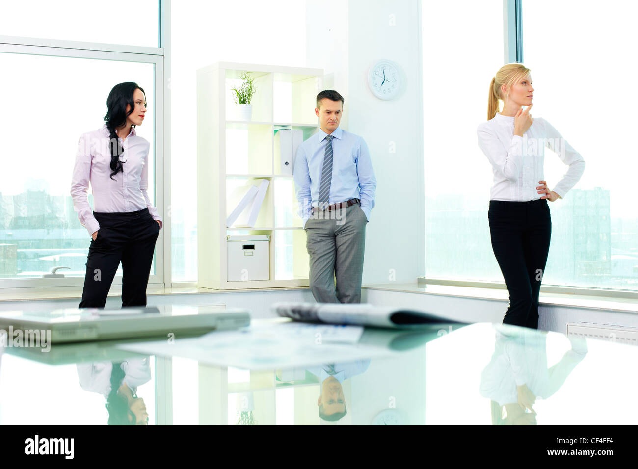 Three pensive business people gathered in office Stock Photo - Alamy