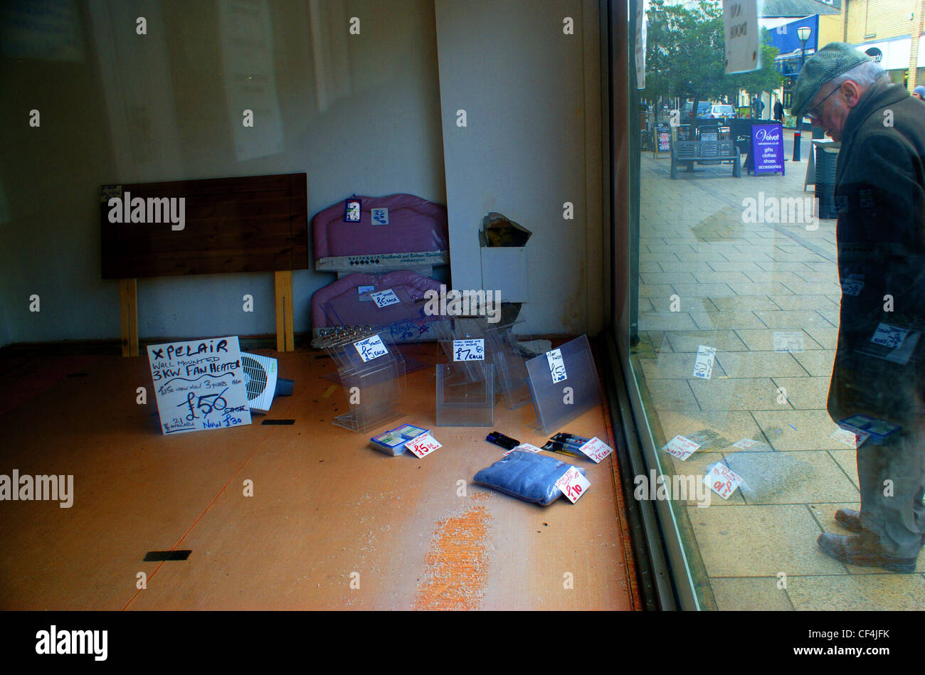 Man staring into shop window at small amount of remaining stock as a ...