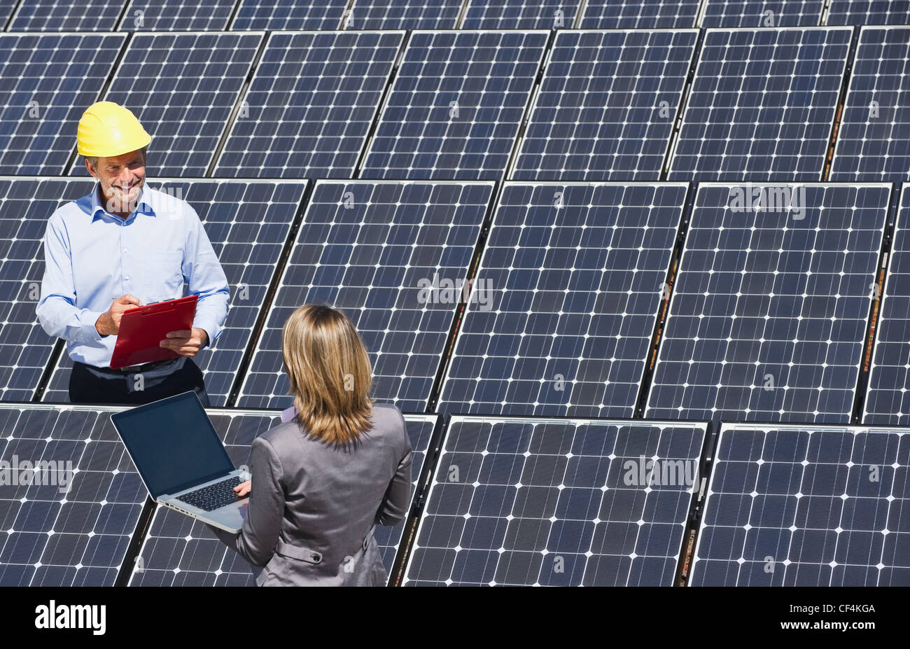 Germany, Munich, Engineers with laptop and discussing in solar plant ...