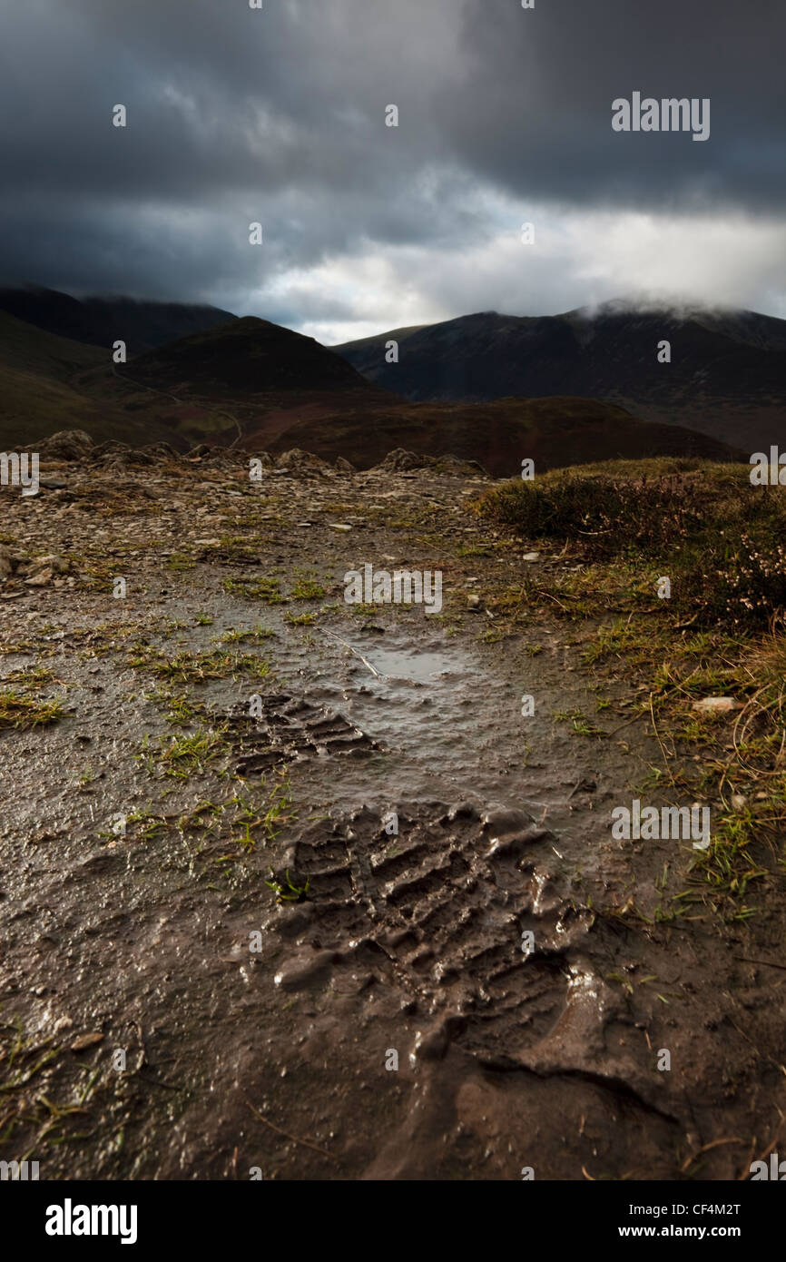 A boot print in mud with a view of the Cumbrian hills behind Stock ...