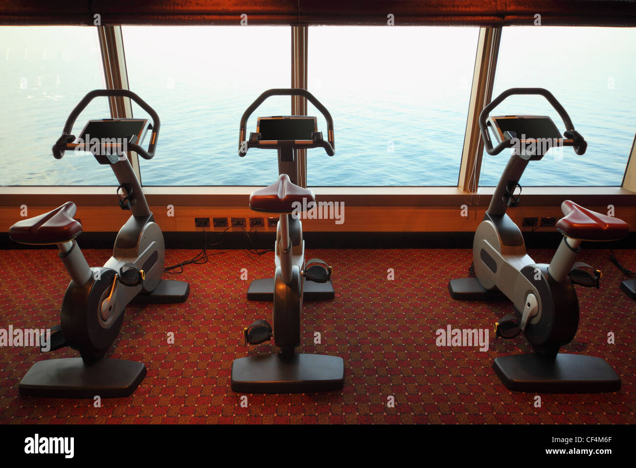 large gym hall with exercise bicycle near window with view on sea in ...