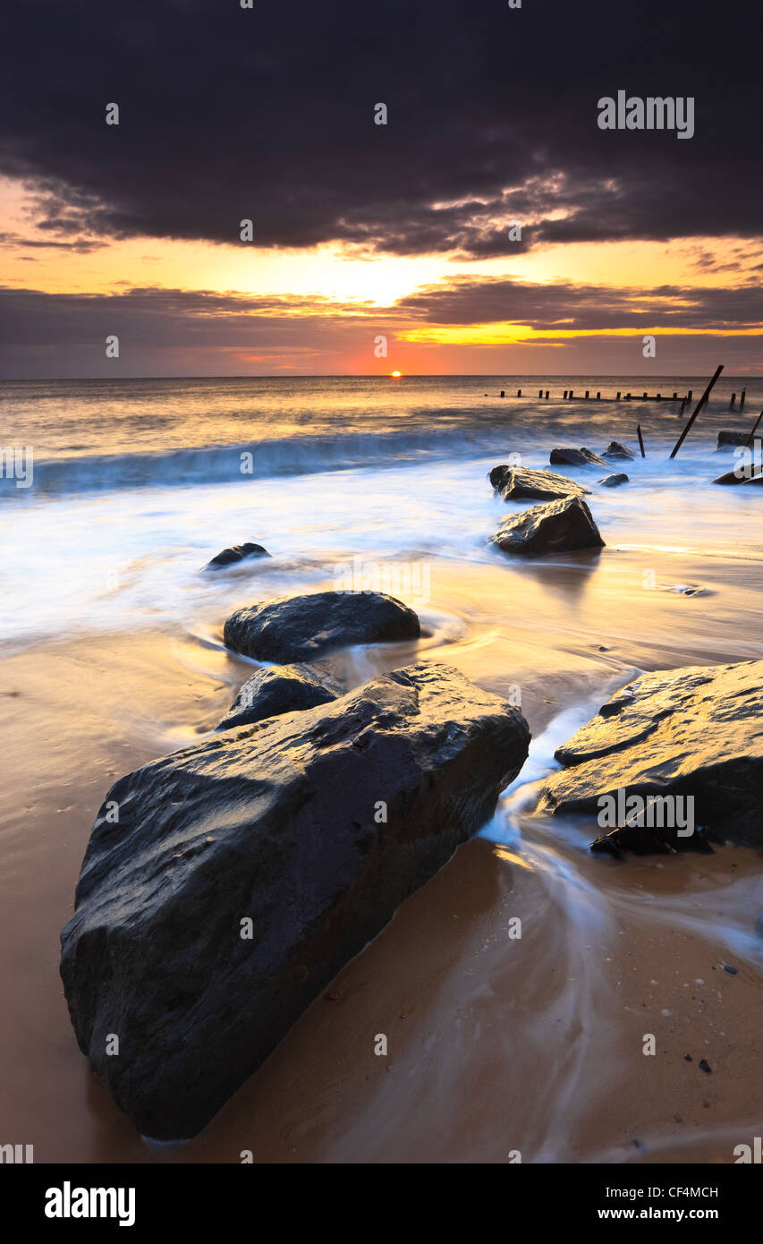 The incoming tide swirls around the rocks of Happisburghs' sea defense ...
