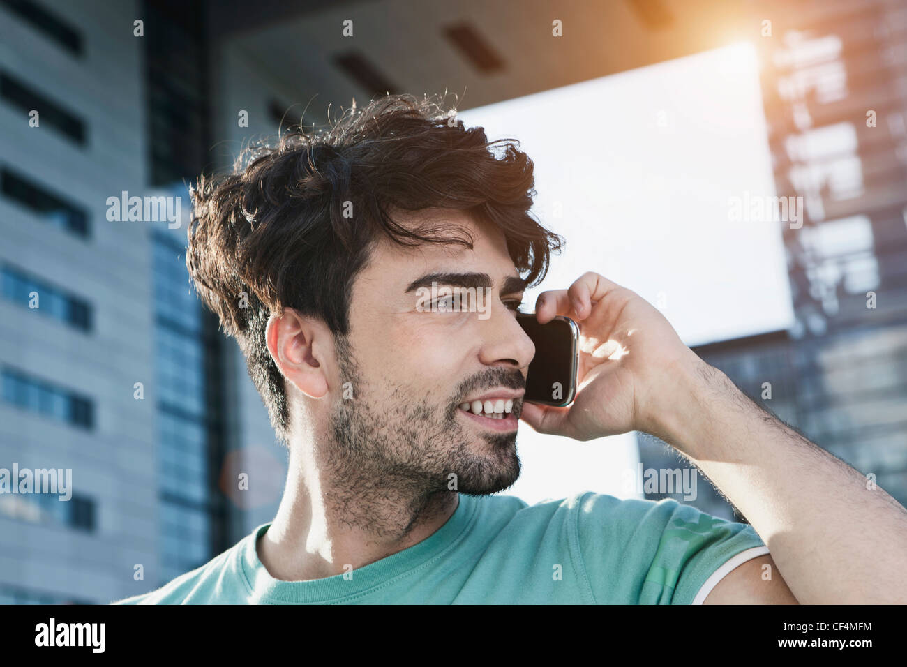 Germany, Cologne, Young man using cell phone, smiling Stock Photo - Alamy
