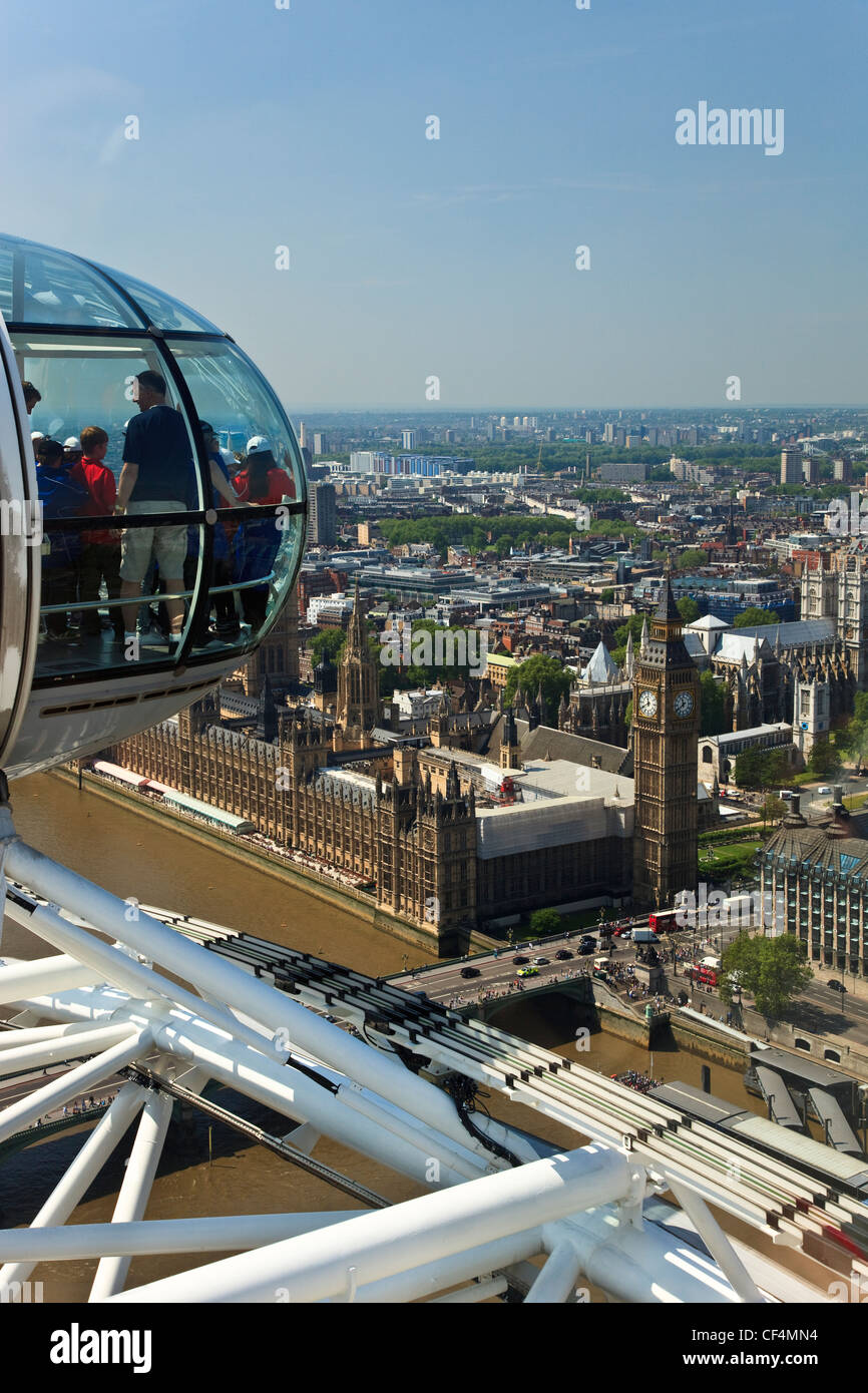 Tourists looking out from a pod on the London Eye towards Big Ben and ...