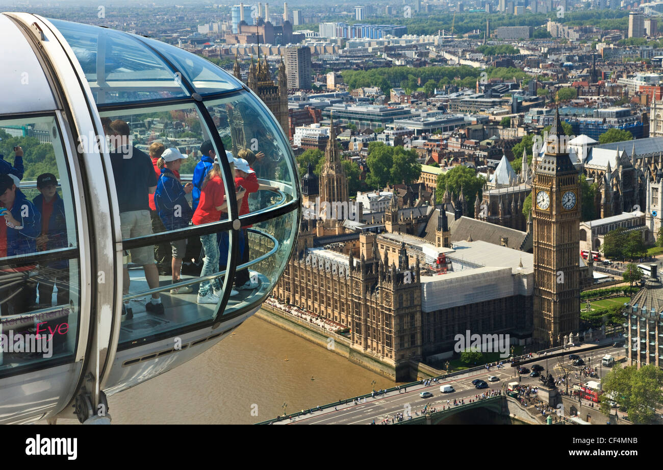 Tourists looking out from a pod on the London Eye towards Big Ben and ...