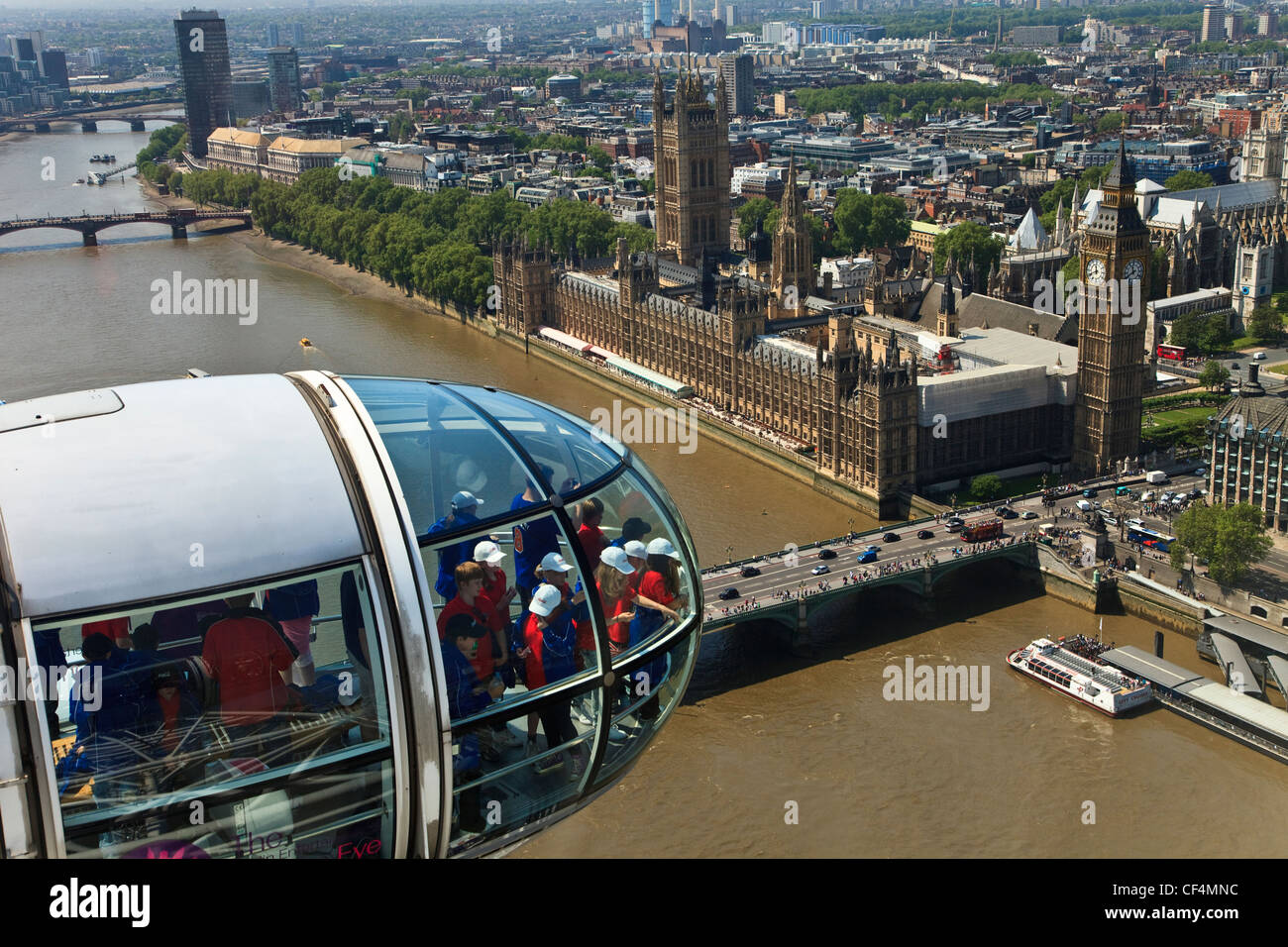 Tourists looking out from a pod on the London Eye towards Big Ben and ...