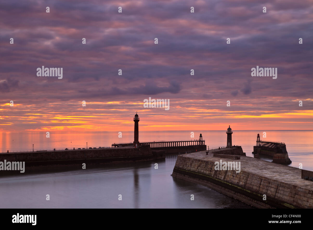 Sunset over the West and East piers at Whitby on a summers evening ...