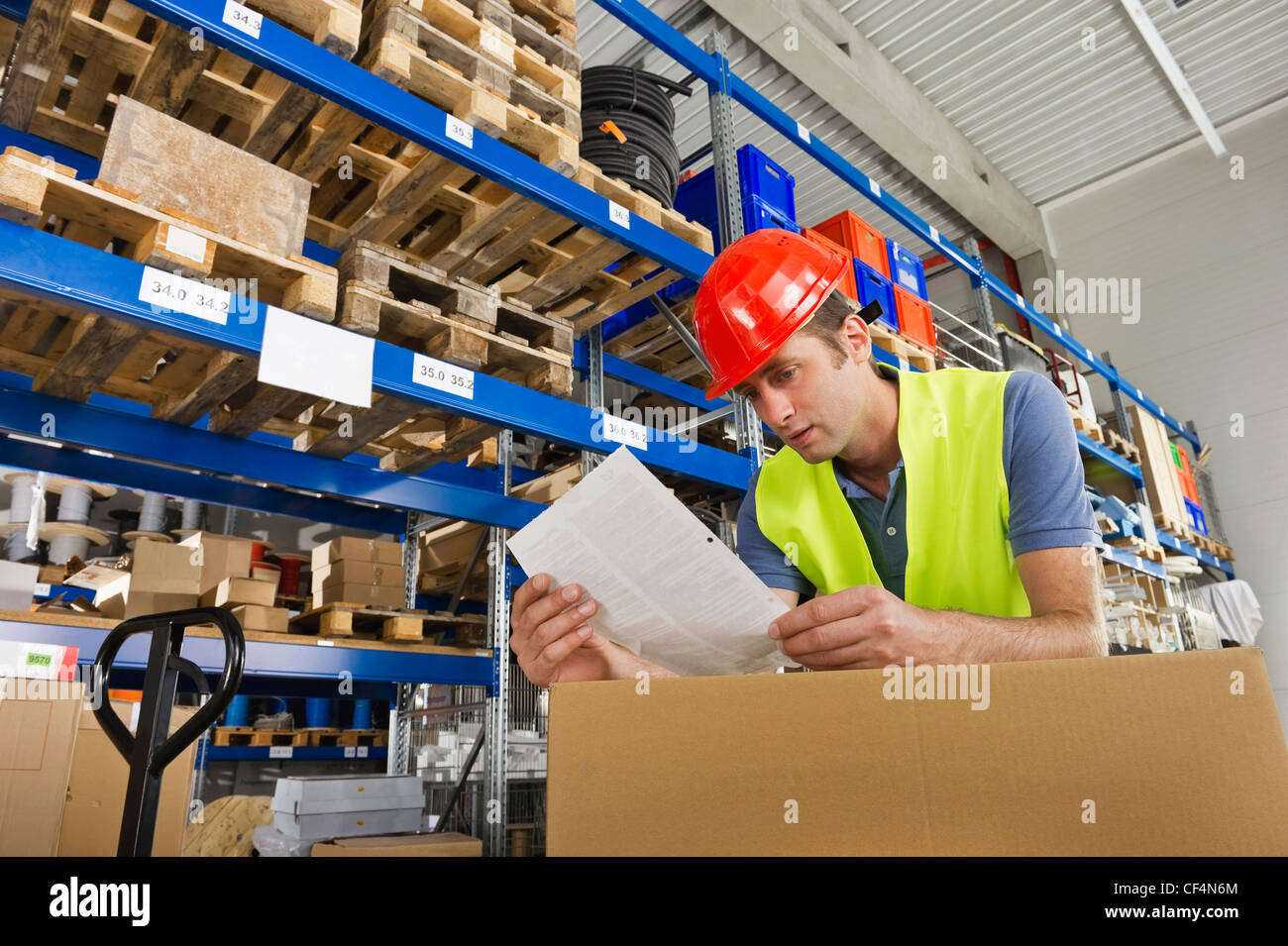 Germany, Bavaria, Munich, Manual worker looking document in warehouse ...
