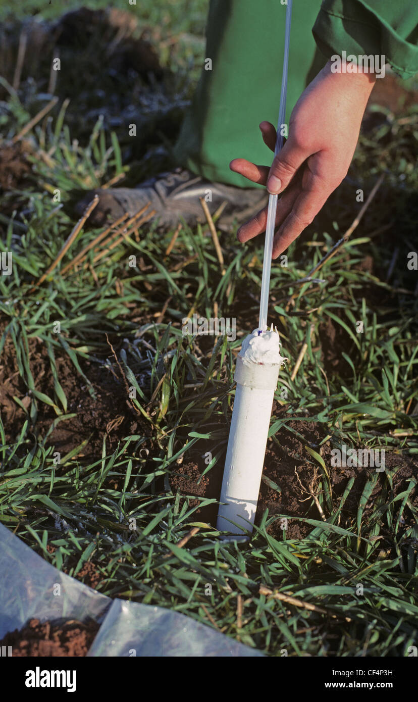 Technician placing a porous pot in the bore hole to monitor chemical ...