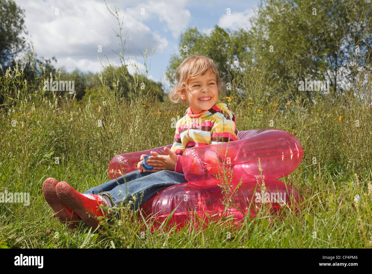 young girl in summer day rest in the open air sitting on an inflatable ...