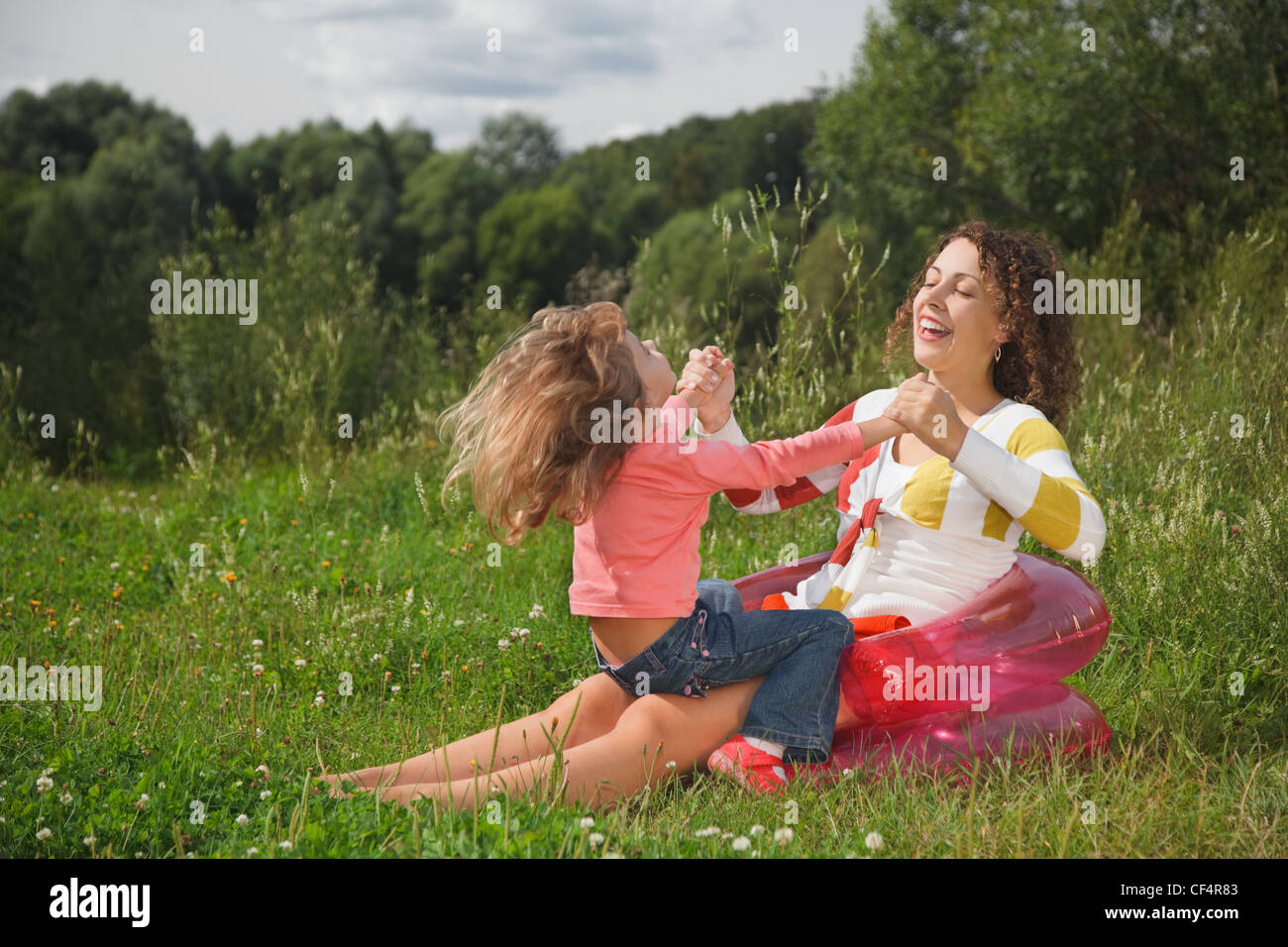 mother and daughter play in the open air, sitting on an inflatable ...
