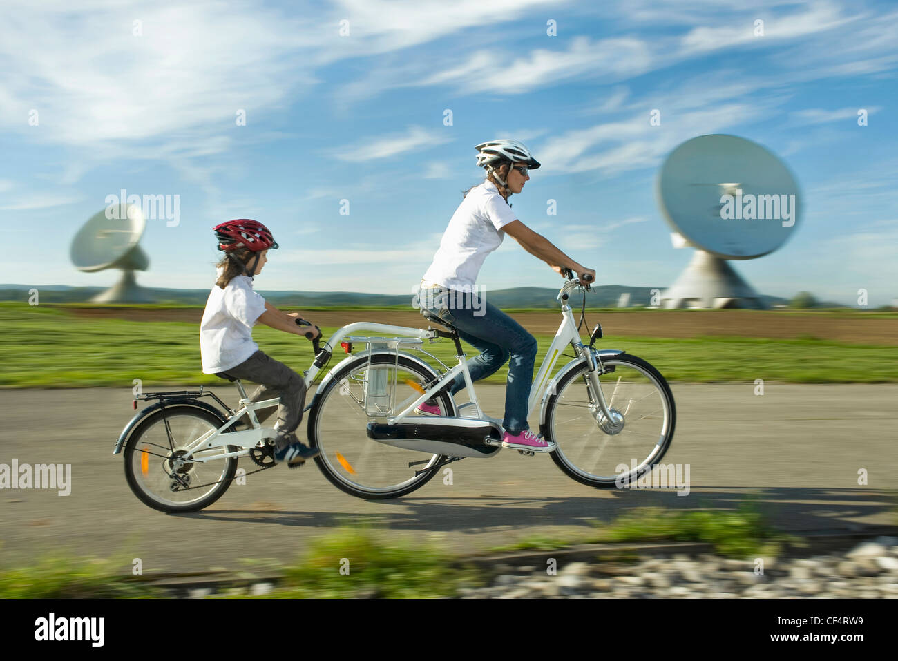 Germany, Bavaria, Raisting, Woman with girl riding electric bicycle ...