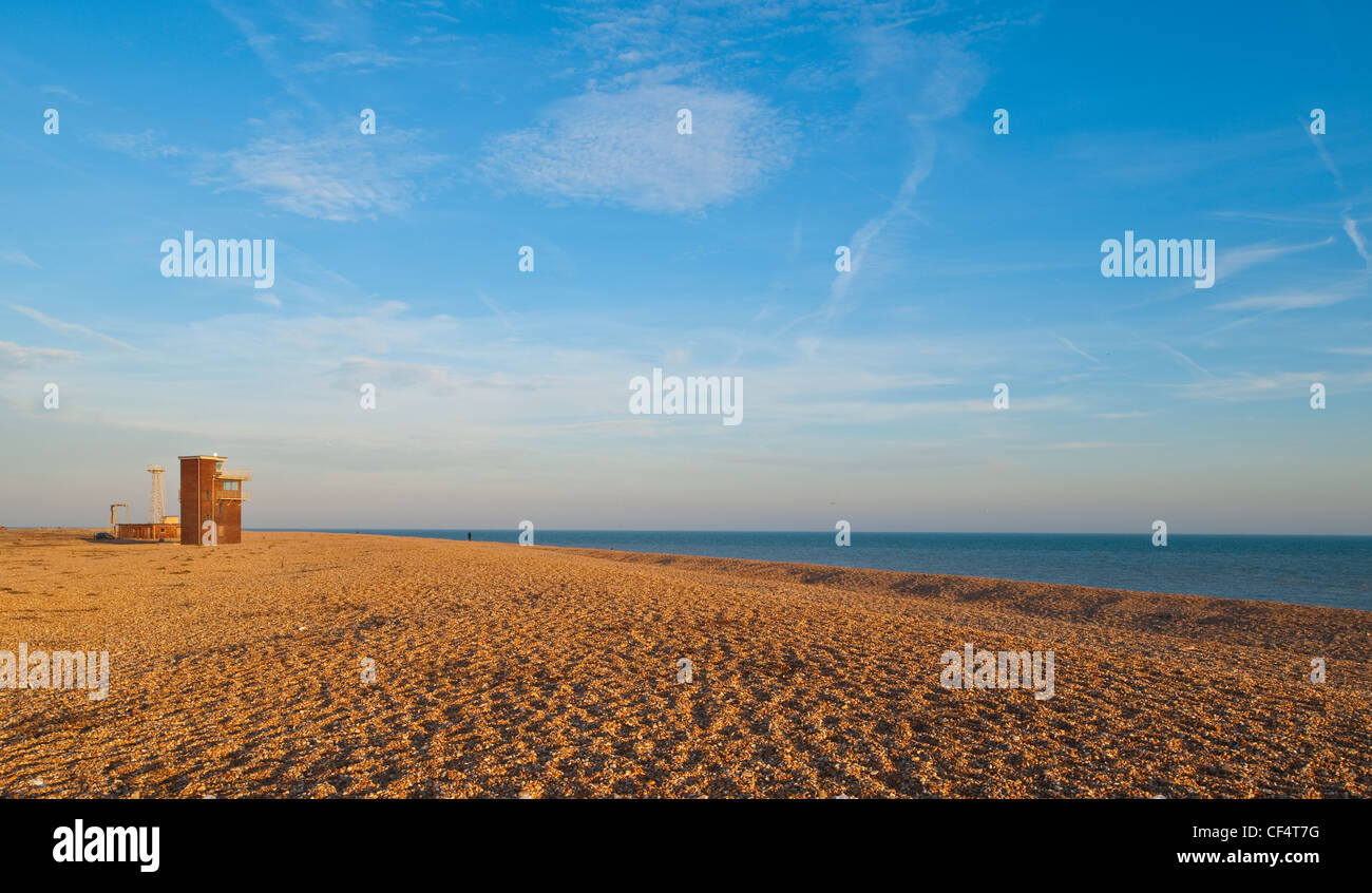 A lone person walking along the shore past houses on the beach at ...