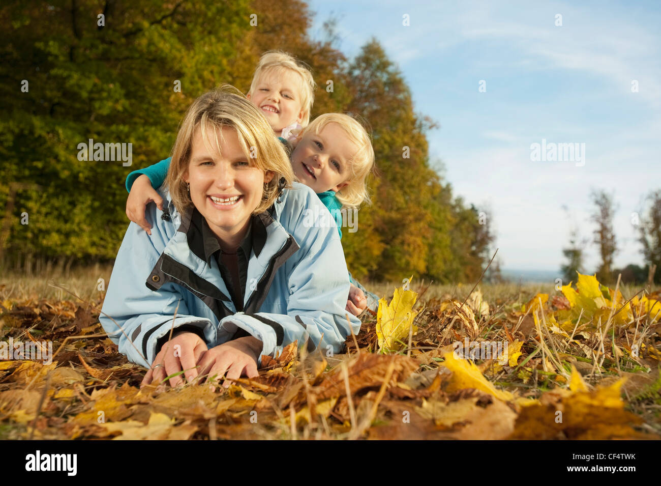 Germany, Bavaria, Family lying on leaves during autumn, smiling ...