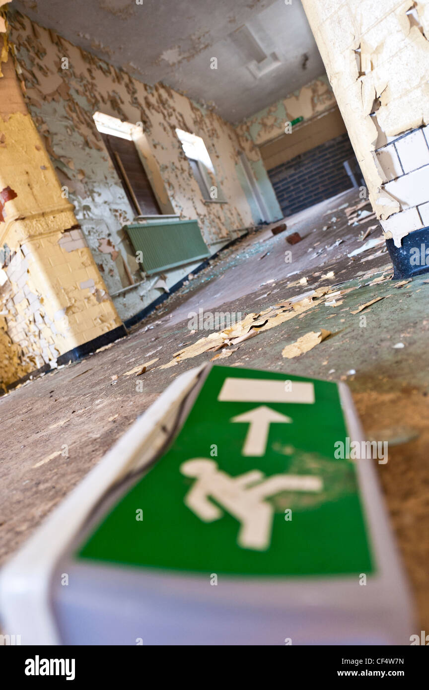 Emergency exit sign on the floor of a derelict hospital, with arrow ...