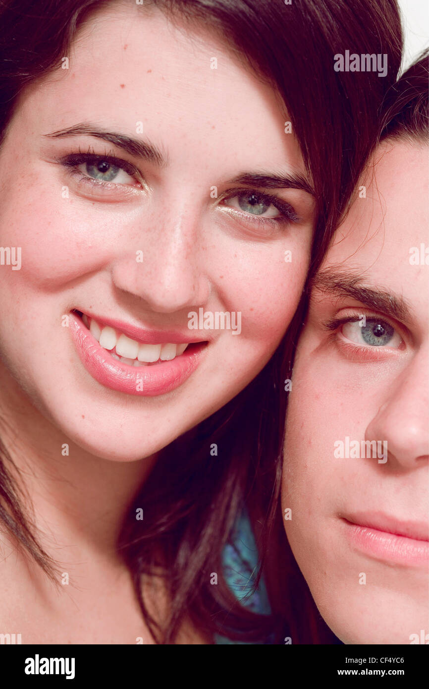 Close up of teenage couple cheek to cheek, female smiling showing teeth ...