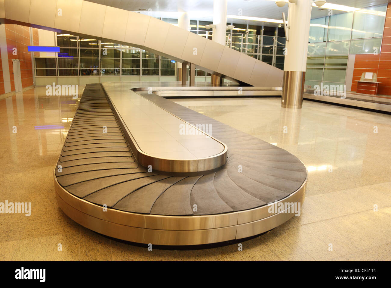 empty baggage carousel in airport hall with granite floor and glass ...