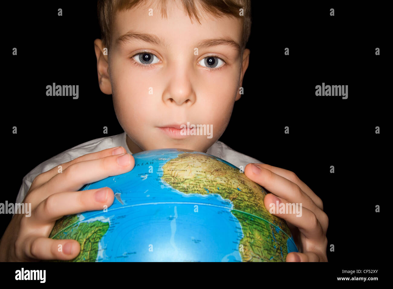 boy keeps in hands over globe of world isolated on black background ...