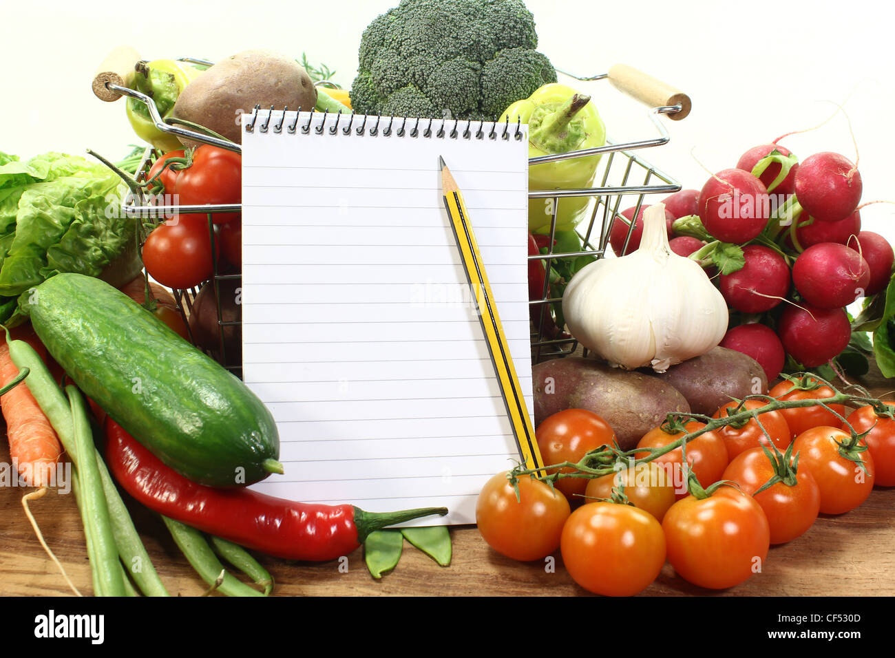Shopping list with basket, pencil and fresh vegetables on a wooden ...