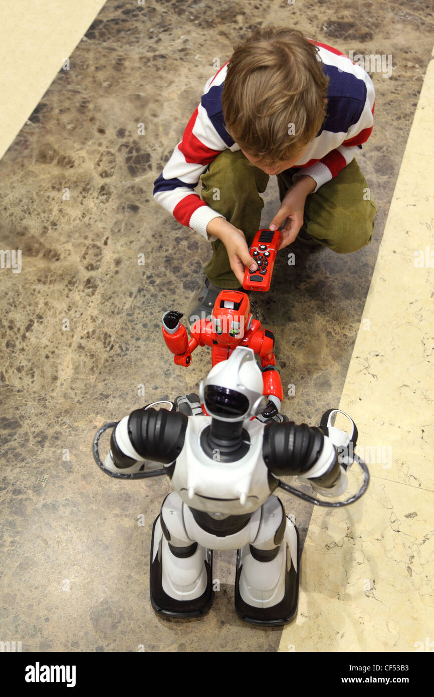 little boy playing with two radio controlled robots view from above ...
