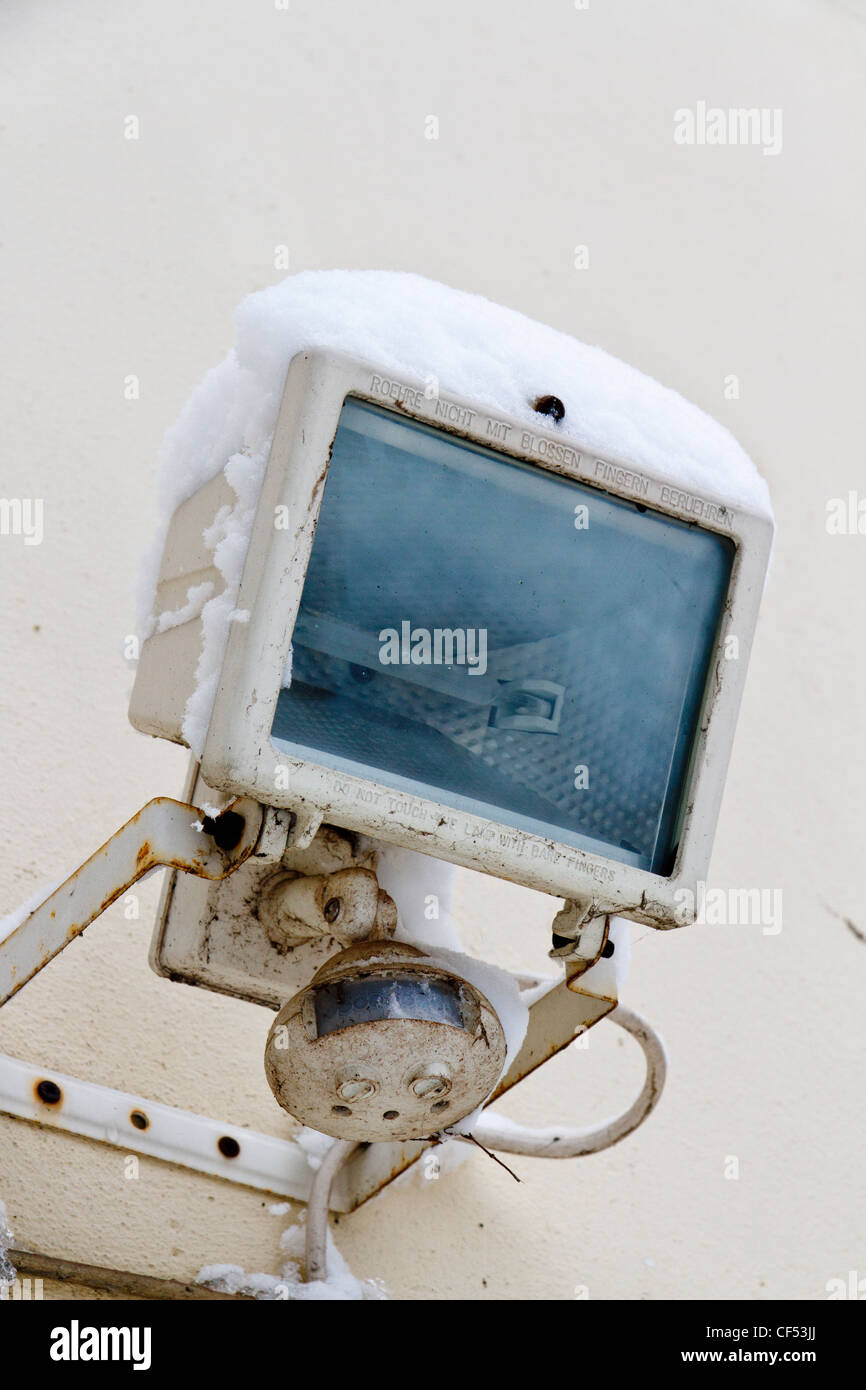 Snow covered wall mounted exterior security light Stock Photo - Alamy