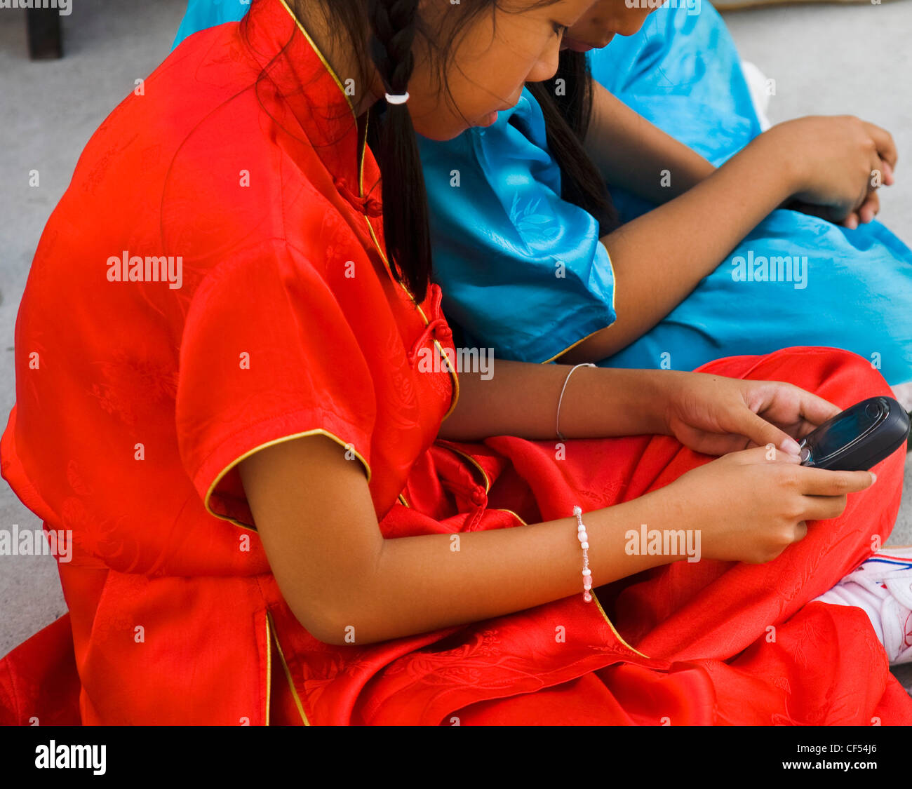 Thailand, Bangkok, Young Thai girl using mobile telephone seated with ...