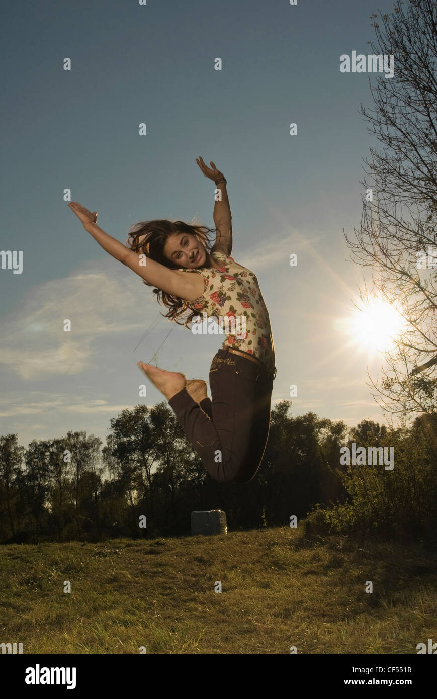Germany, Bavaria, Fuerstenfeldbruck, Young woman jumping in grass ...