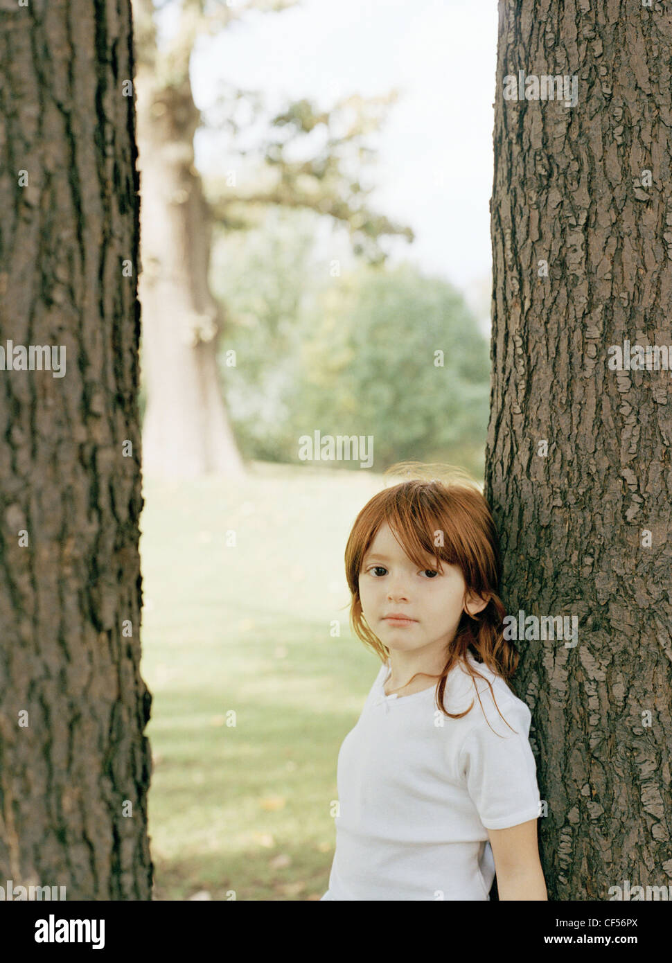 Female child standing leaning against tree Stock Photo - Alamy