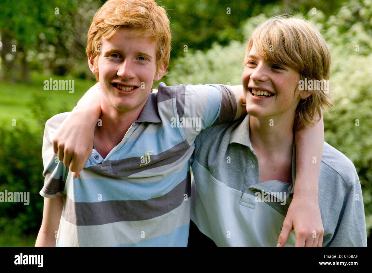 Two male teenagers standing with arms around each others shoulders ...