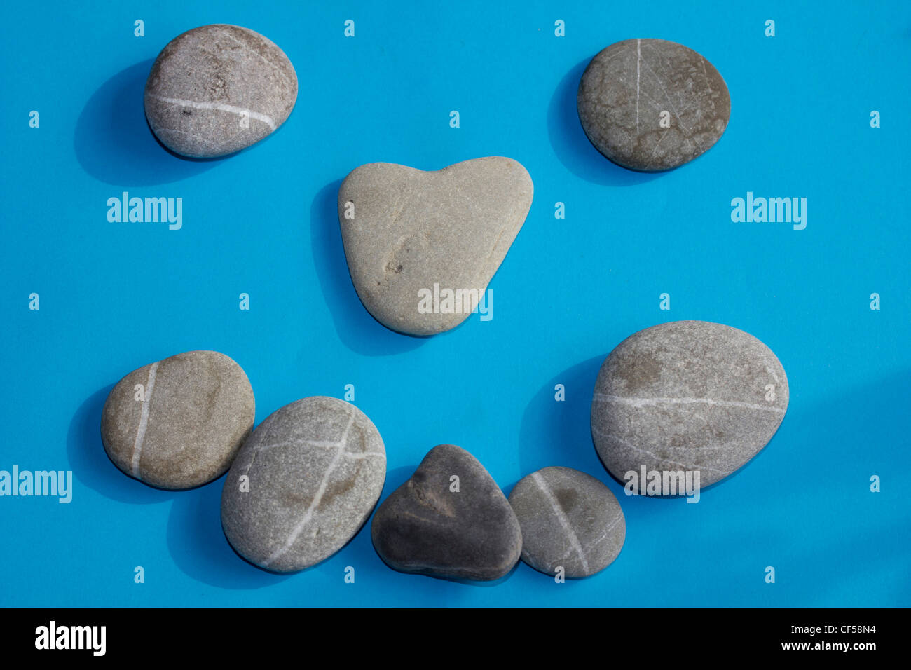 Smiley Happy face Pebbles on a blue background Stock Photo - Alamy