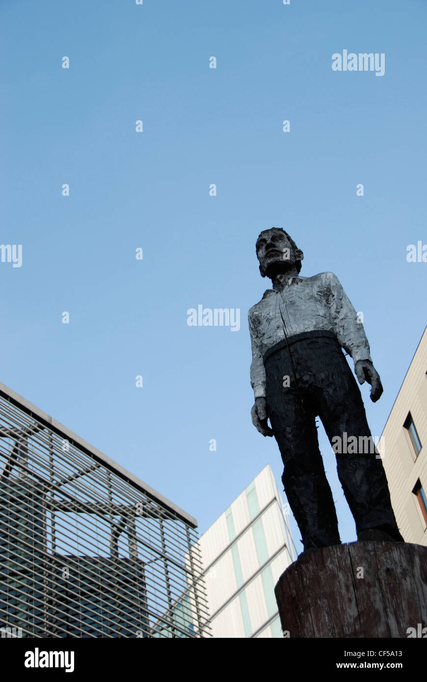 A wooden statue of male office worker and contemporary buildings at the ...