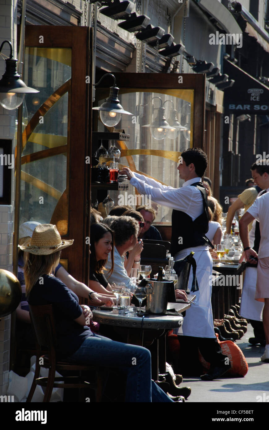 A waiter and customers outside a bar restaurant in Old Compton Street ...