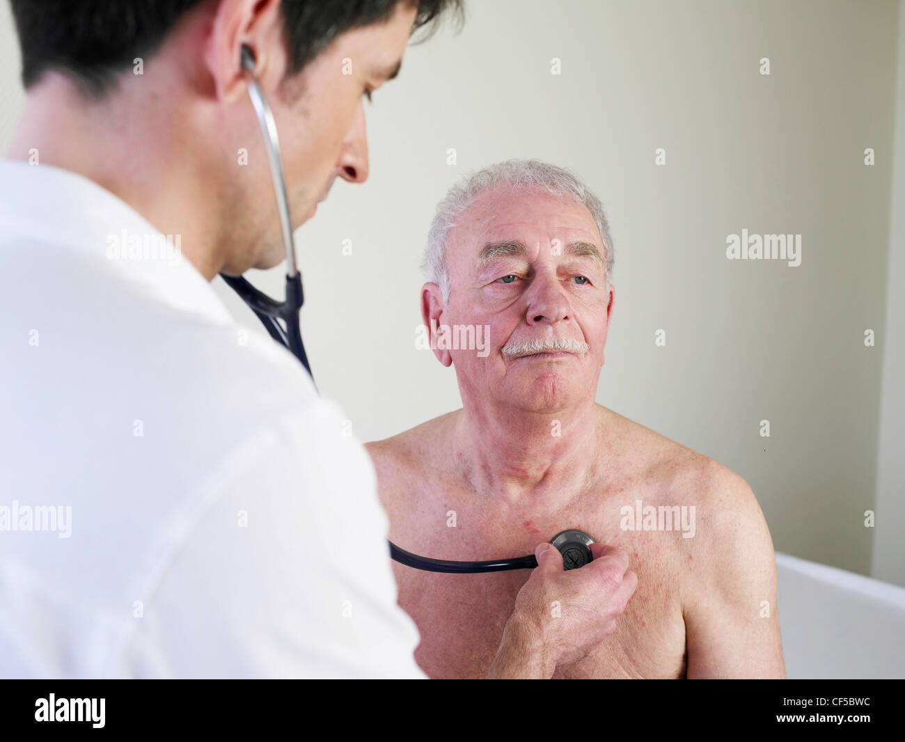 Germany, Hamburg, Doctor examining patient with stethoscope in clinic ...